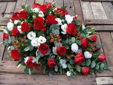 Klassiek rouwstuk van o.a rode rozen en witte lisianthus.